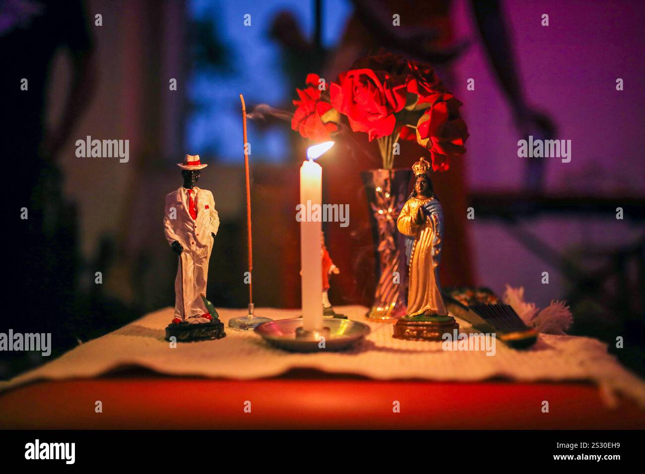 An altar featuring Umbanda deities, a candle and flowers is installed ...