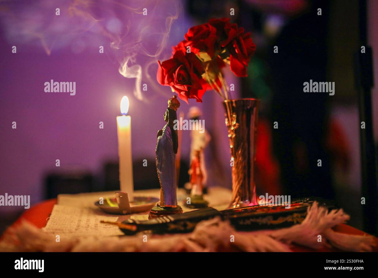 An altar featuring Umbanda deities, a candle and flowers is installed ...