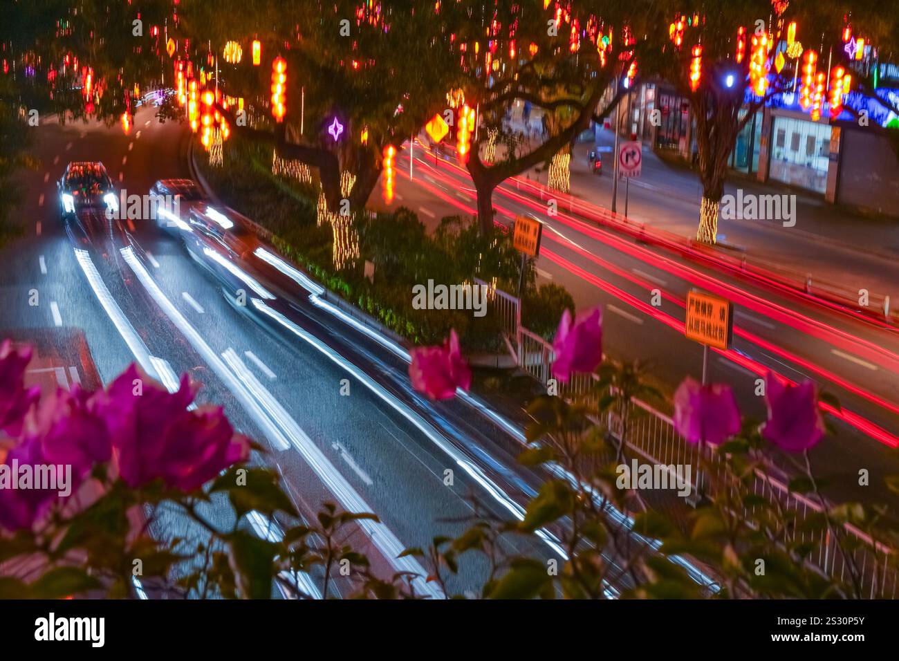 Vehicles drive along a road decorated with red lanterns on both sides ...