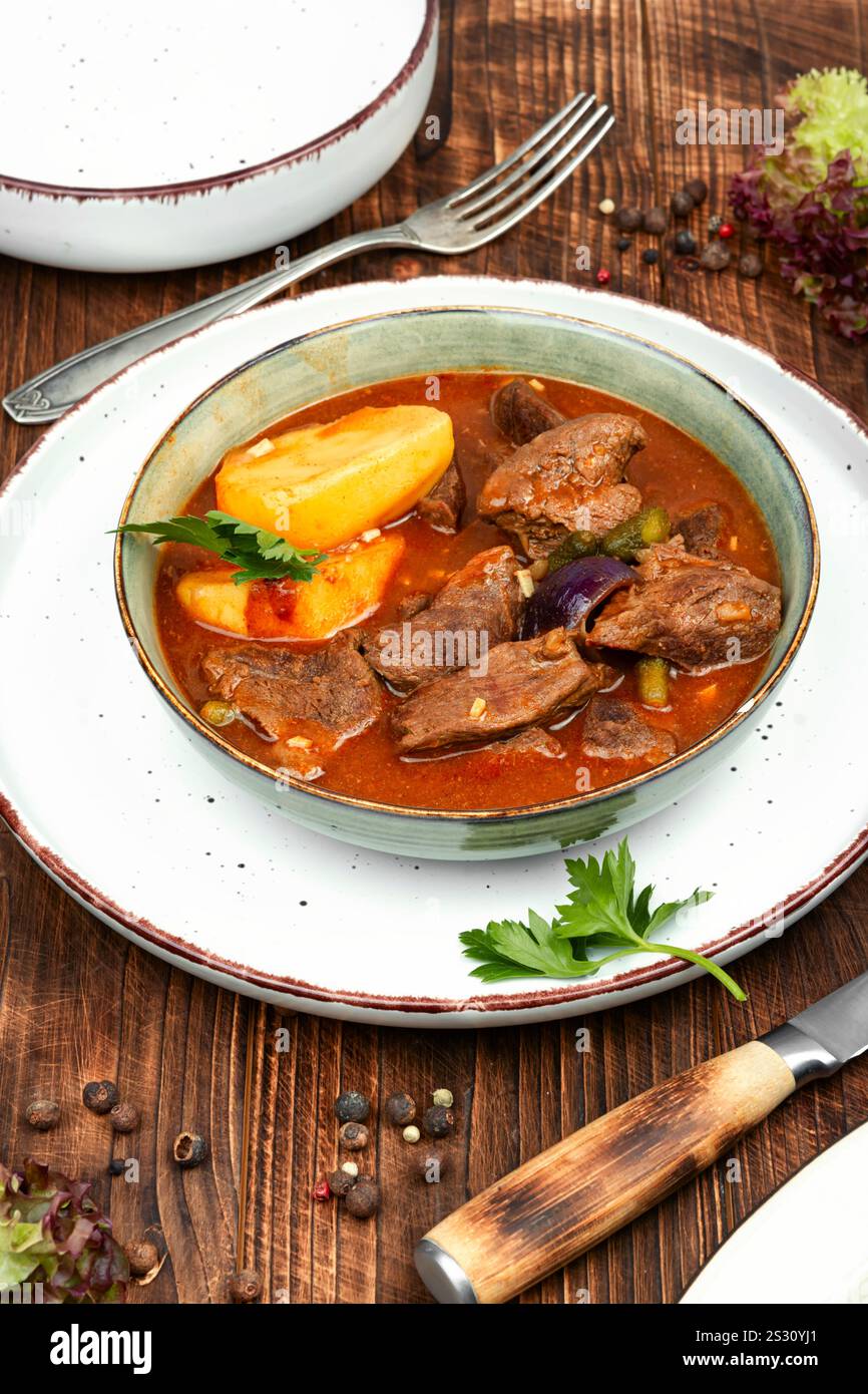 Stewed deer goulash in sauce, venison goulash. Deer ragout on rustic ...