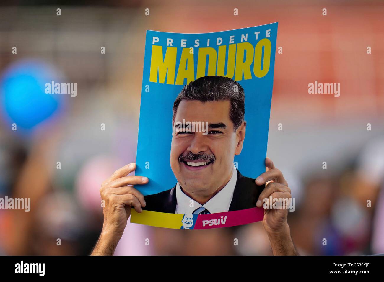 FILE - A supporter displays a poster of President Nicolas Maduro during ...