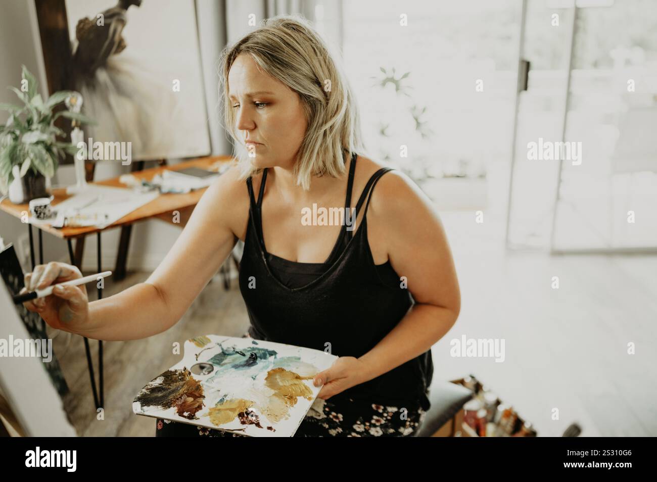 Art, focus and painting, woman in studio at home with brush, canvas and ...