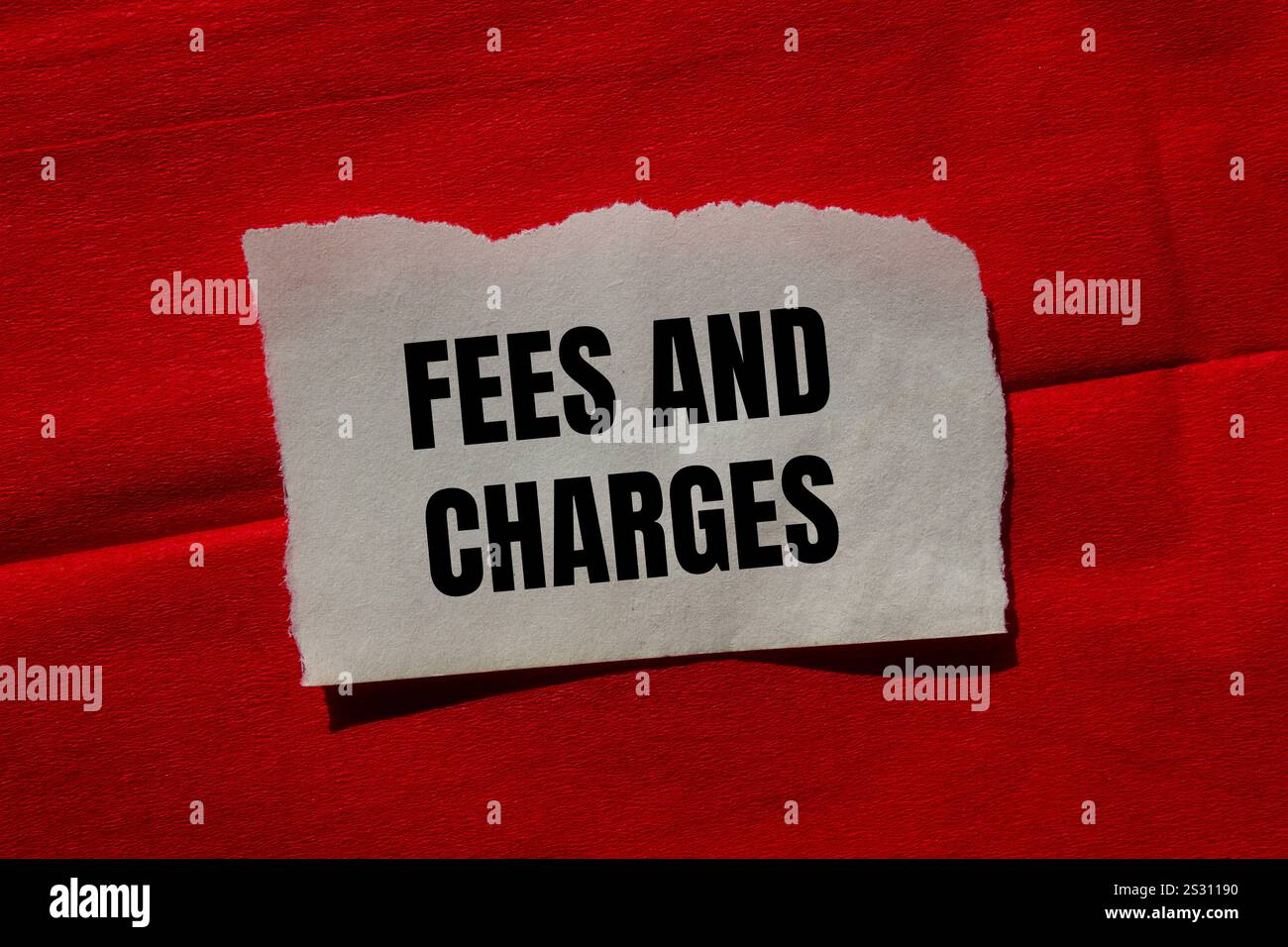 Fees and charges message written on ripped torn paper piece on red ...