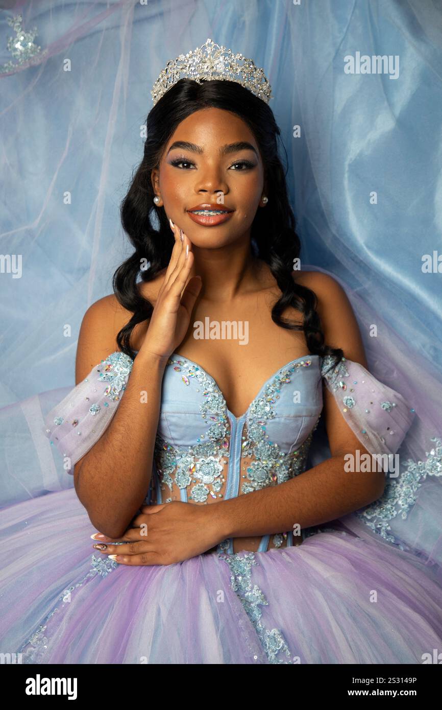 a beautiful quinceañera in a blue dress posing with her hand on her face Stock Photo - Alamy