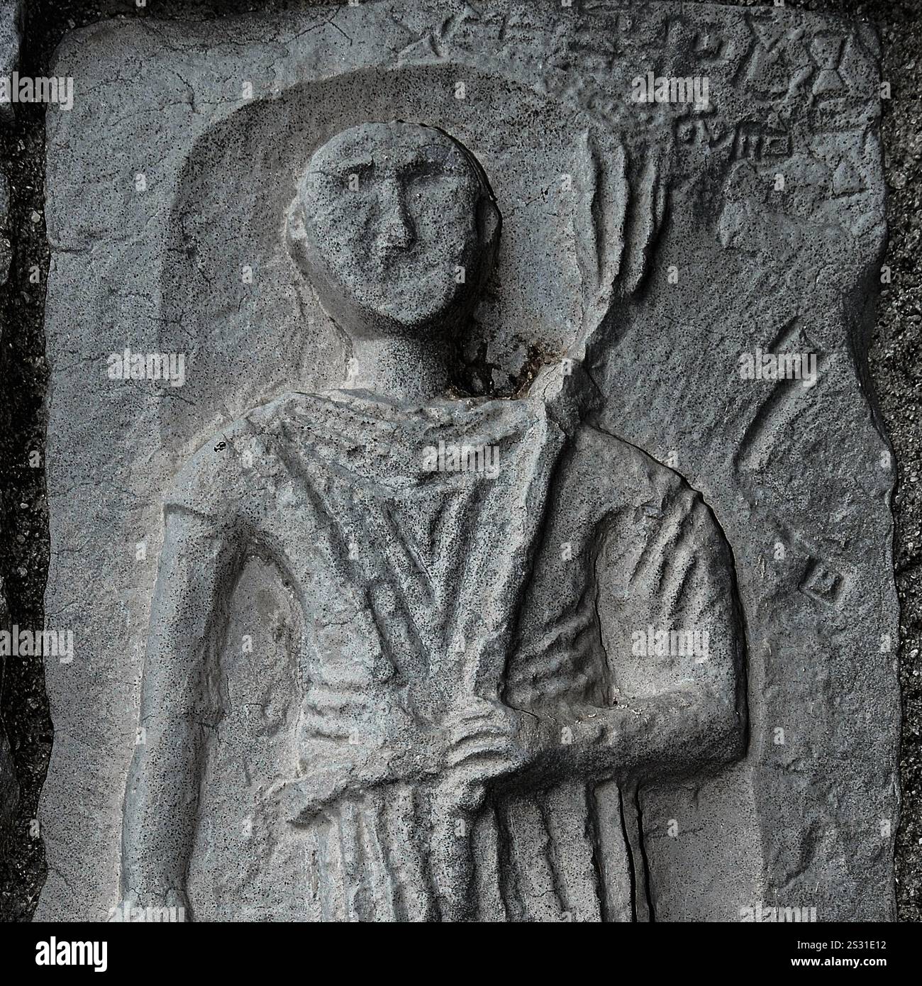 Below a Glagolitic inscription a tunic-wearing man holds a branch with ...