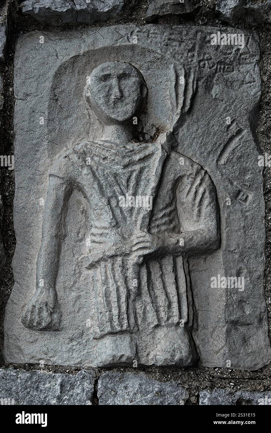 An 11th century relief of a tunic-wearing man holding a branch with ...