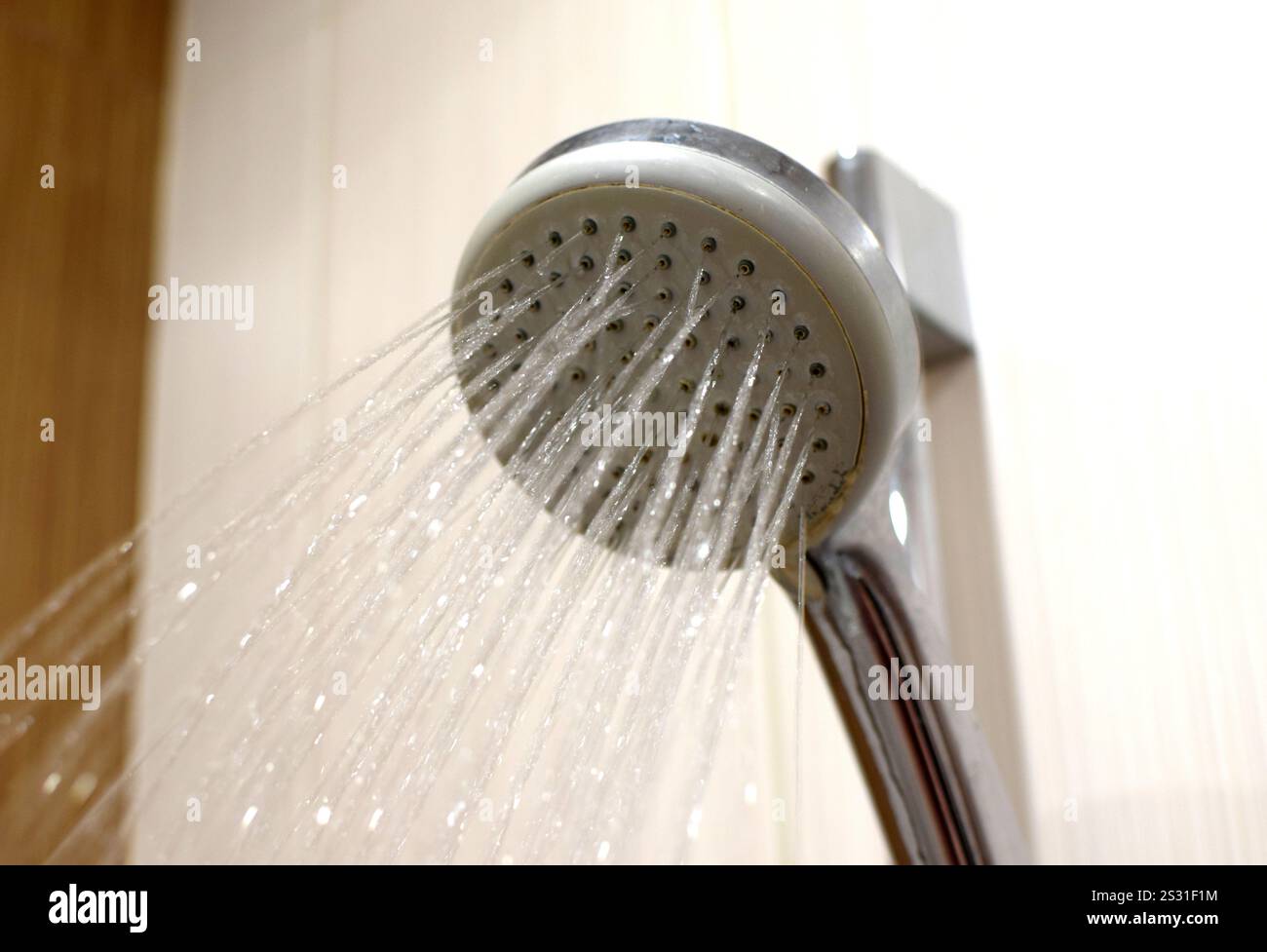 Water is pouring out of the shower head. The shower head is covered ...