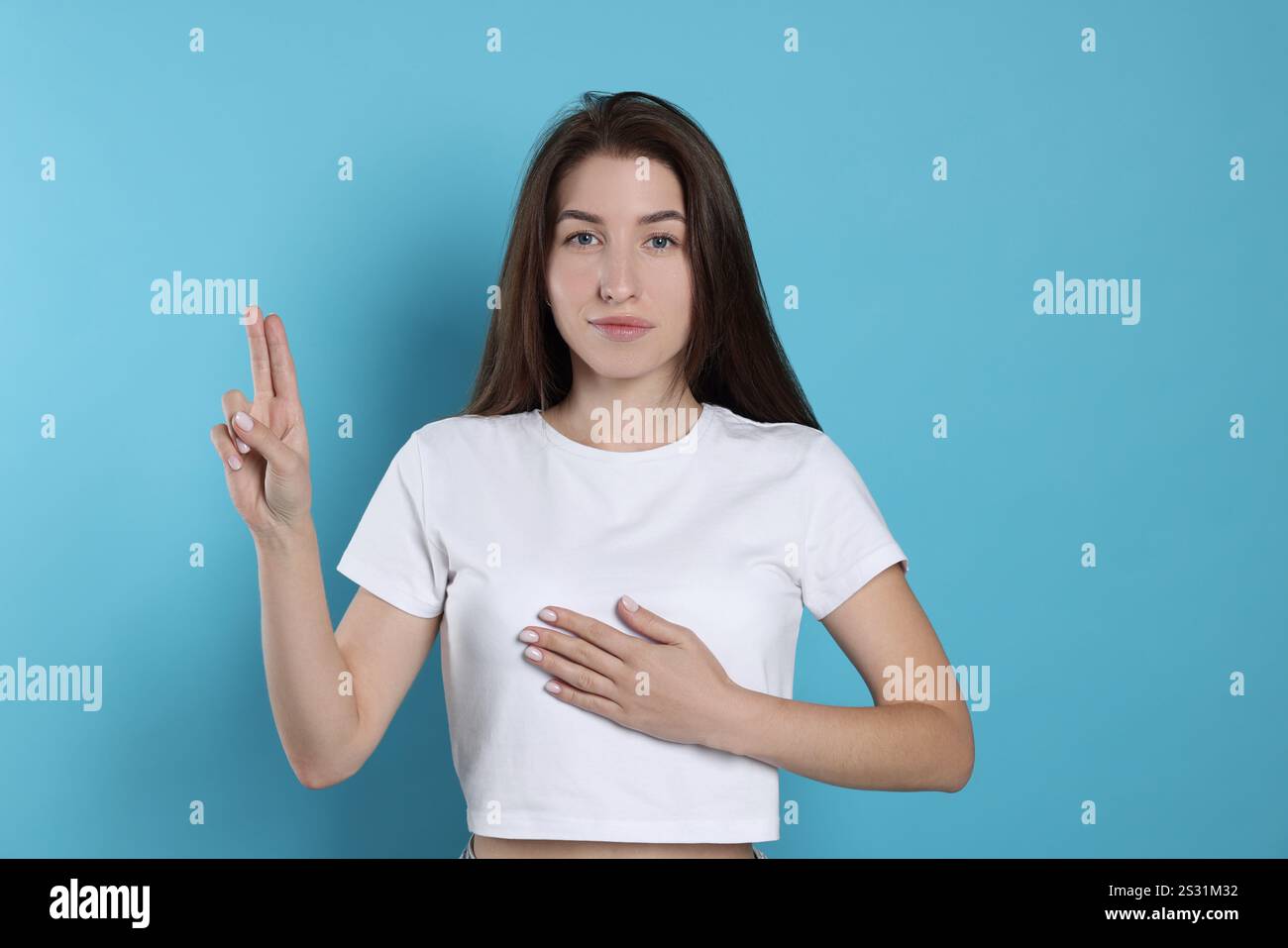 Woman showing oath gesture on light blue background. Making promise ...