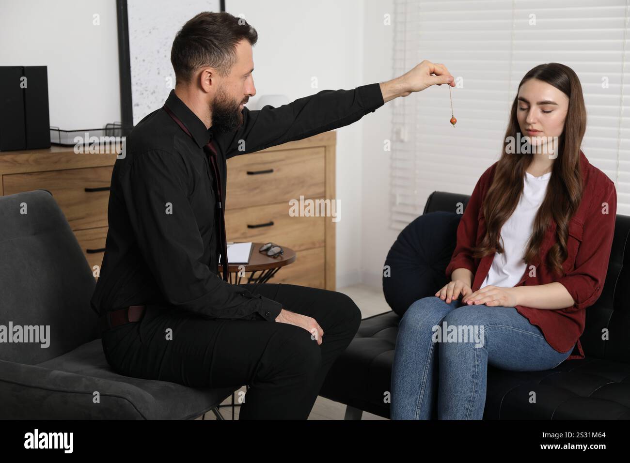 Psychologist using pendulum while working with patient during hypnosis ...
