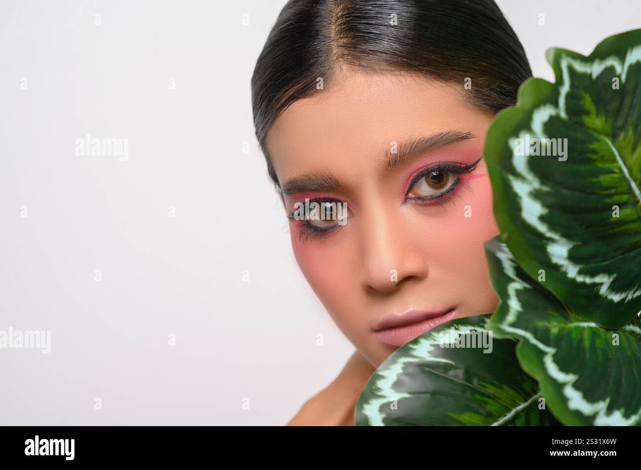 The woman put on pink makeup and decorated with leaves. Isolated on ...