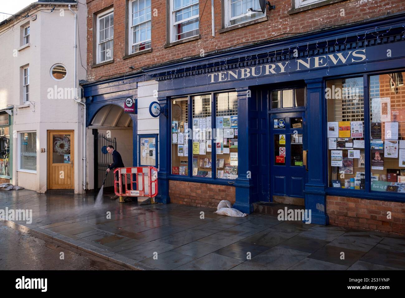 Cleaning up silt and mud outside Tenbury News as people in the ...