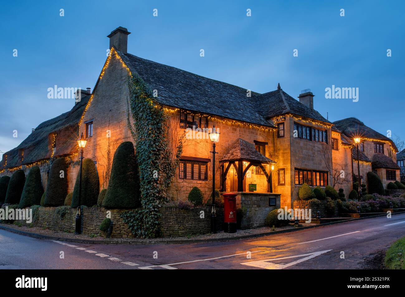 Large stone house with lights in the early morning. Broad Campden ...