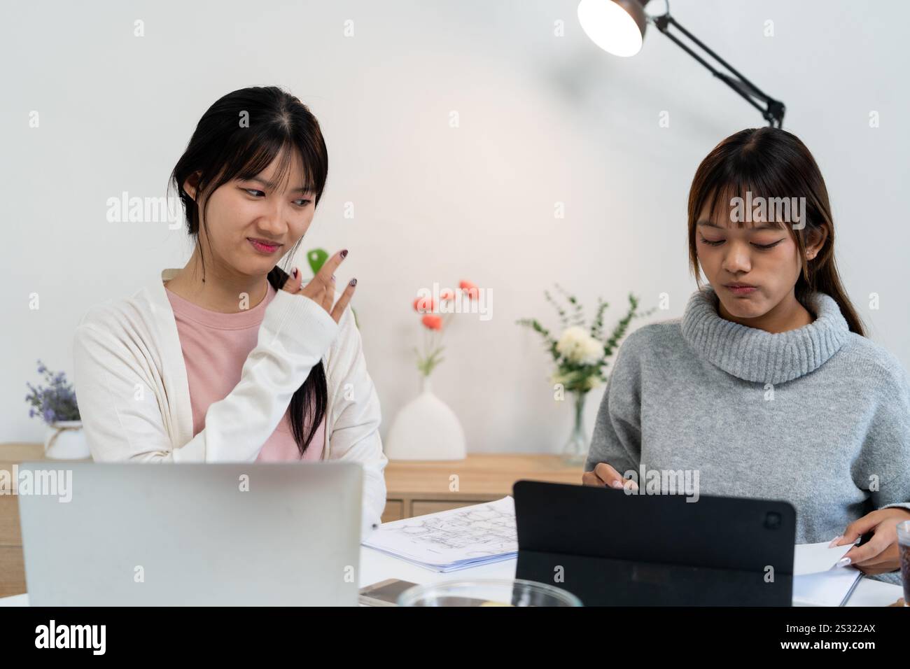 Female higher education student using laptop and studying book in home ...