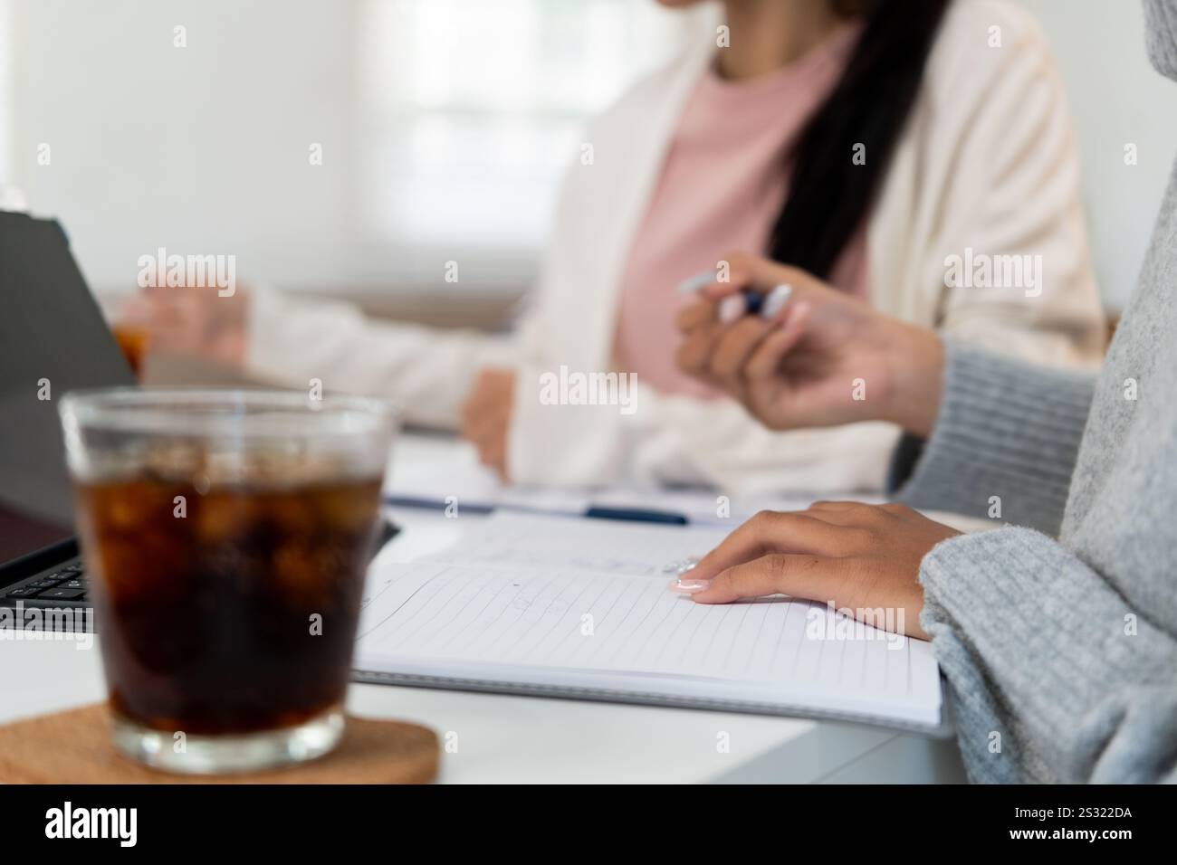 Female higher education student using laptop and studying book in home ...