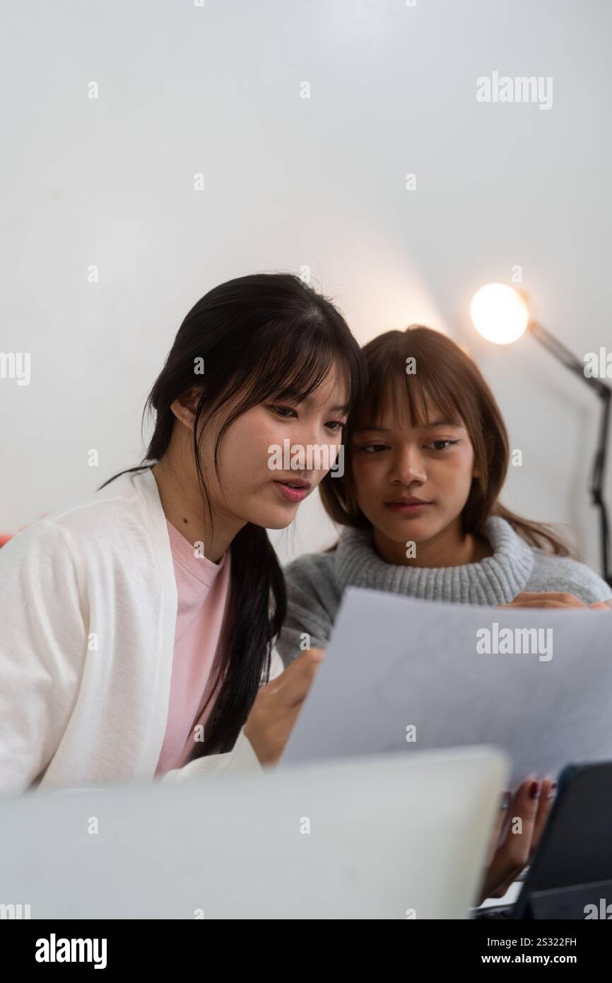 Female higher education student using laptop and studying book in home ...