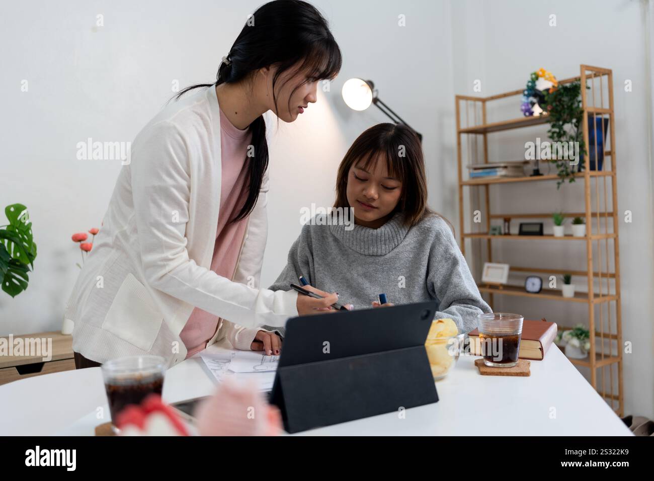 Female higher education student using laptop and studying book in home ...
