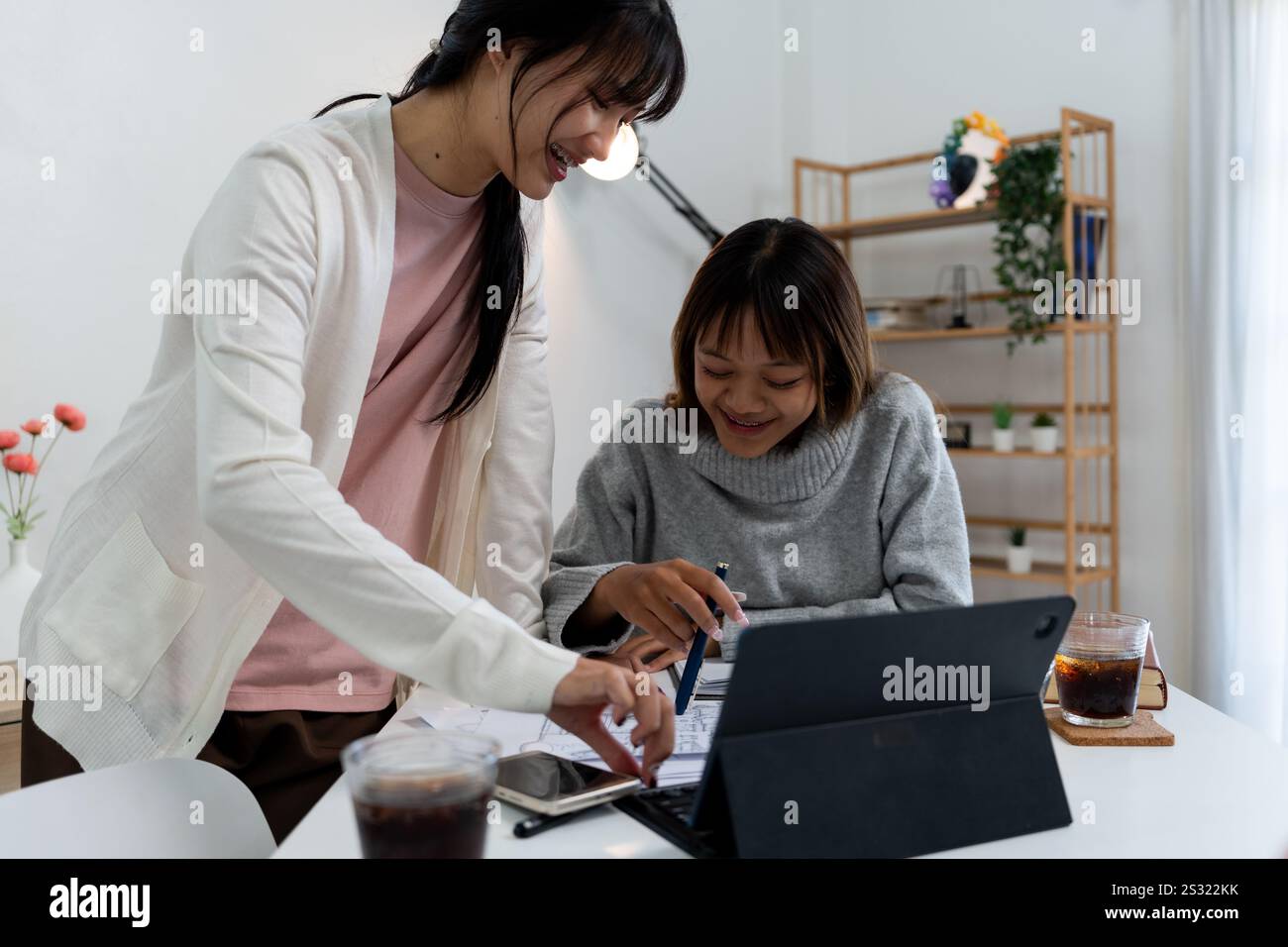 Female higher education student using laptop and studying book in home ...