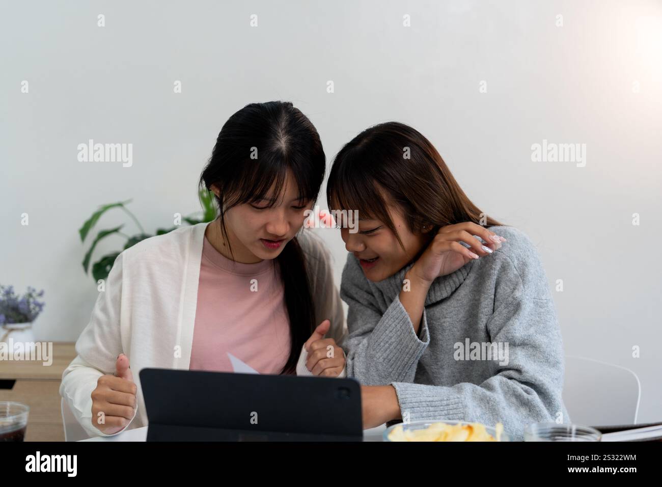 Female higher education student using laptop and studying book in home ...