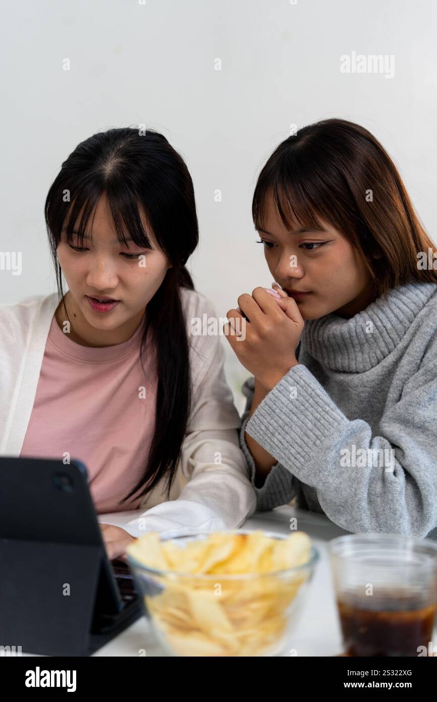 Female higher education student using laptop and studying book in home ...