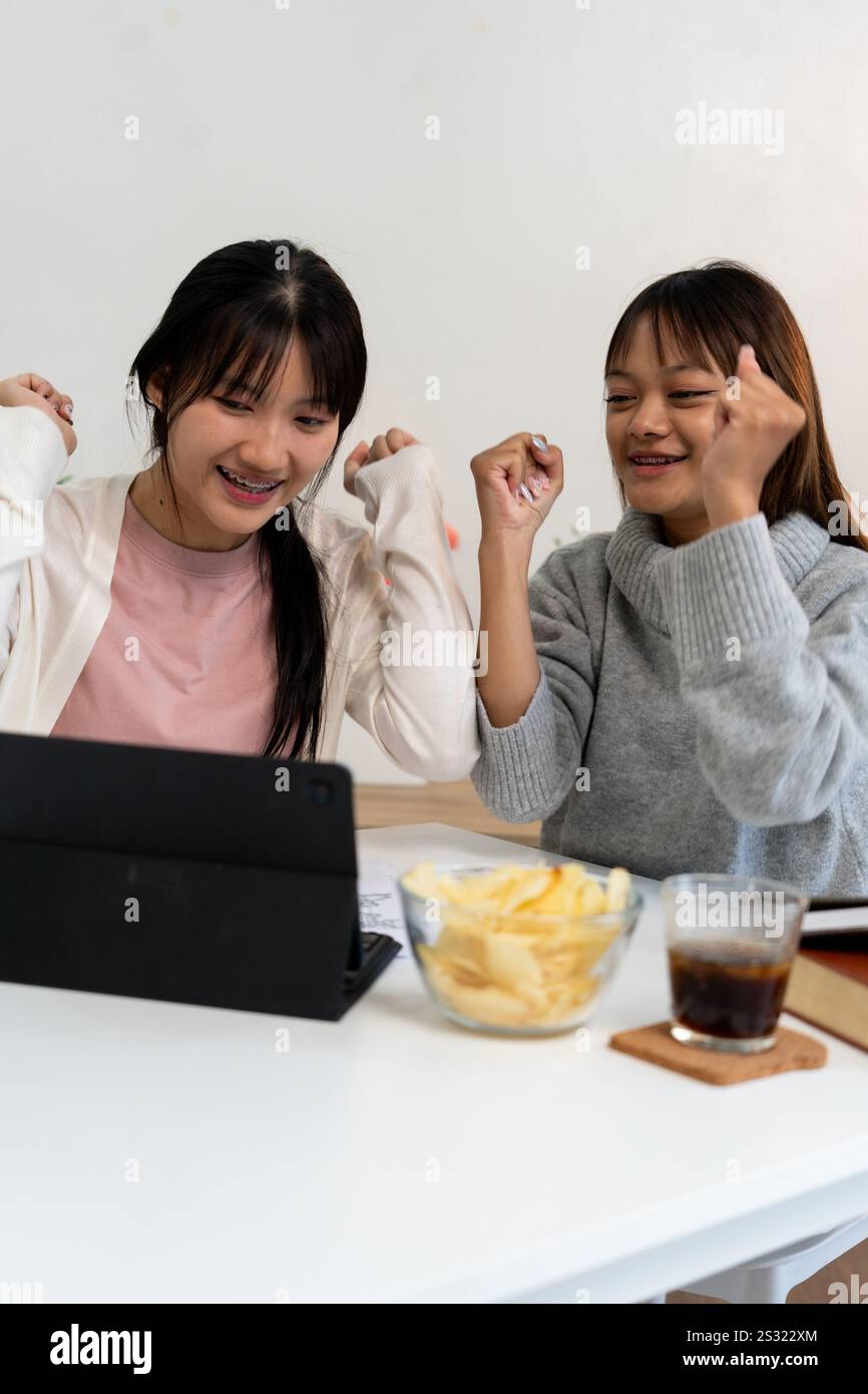 Female higher education student using laptop and studying book in home ...