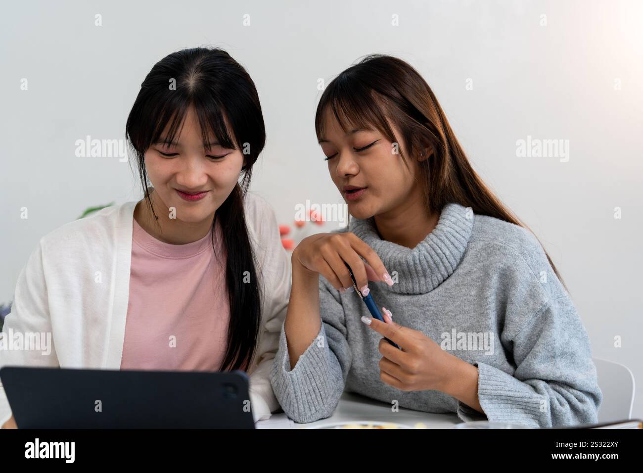 Female higher education student using laptop and studying book in home ...