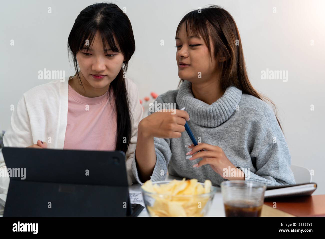 Female higher education student using laptop and studying book in home ...
