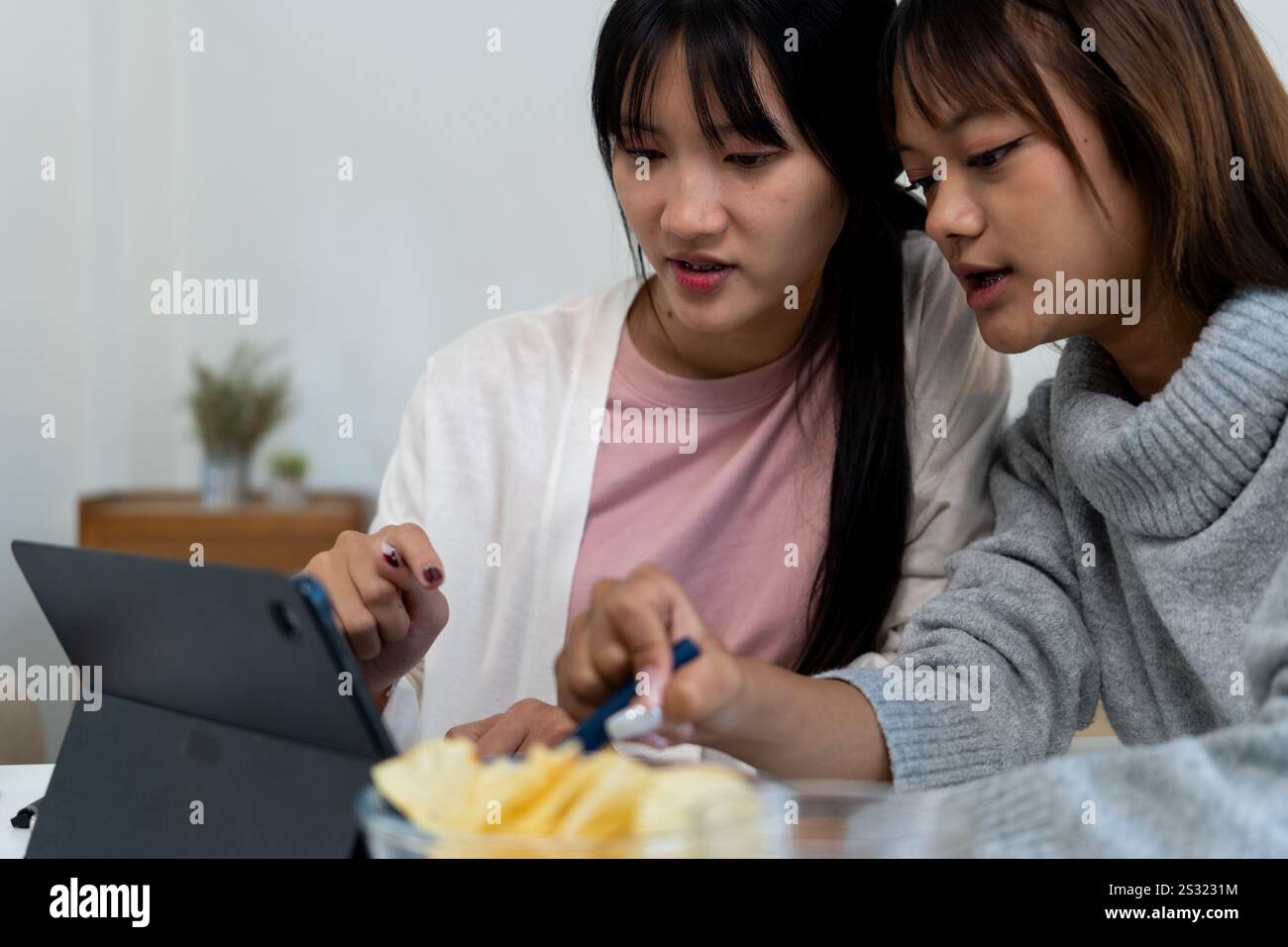 Female higher education student using laptop and studying book in home ...