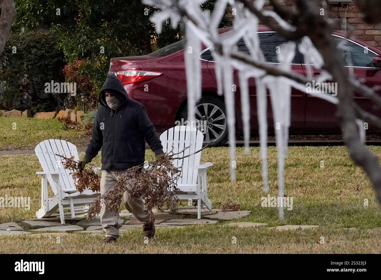 Samuel Sotelo moves branches as cold temperatures and a lawn sprinkler ...