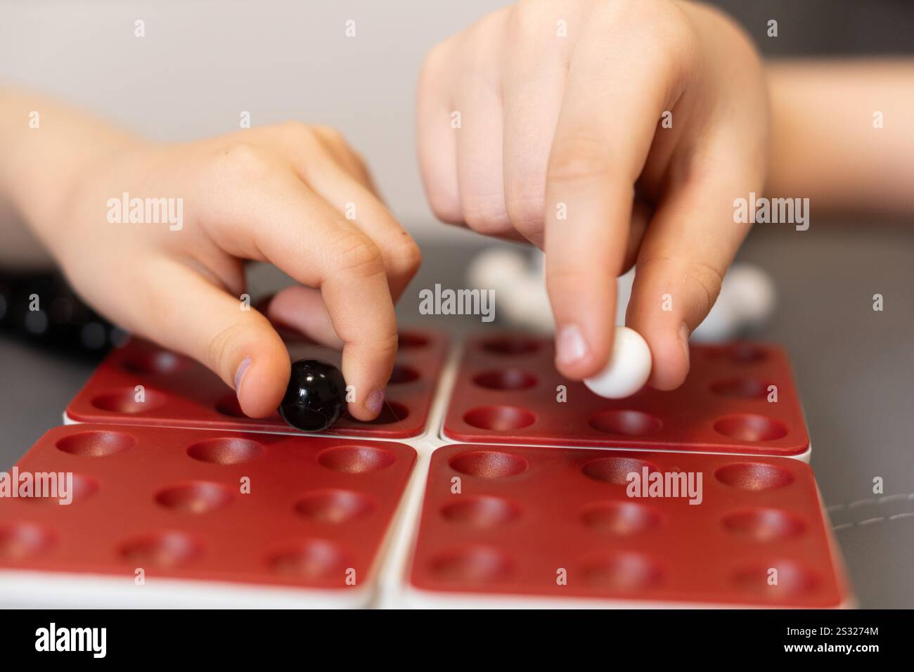 A group of happy children plays a tabletop game, placing marbles on the ...