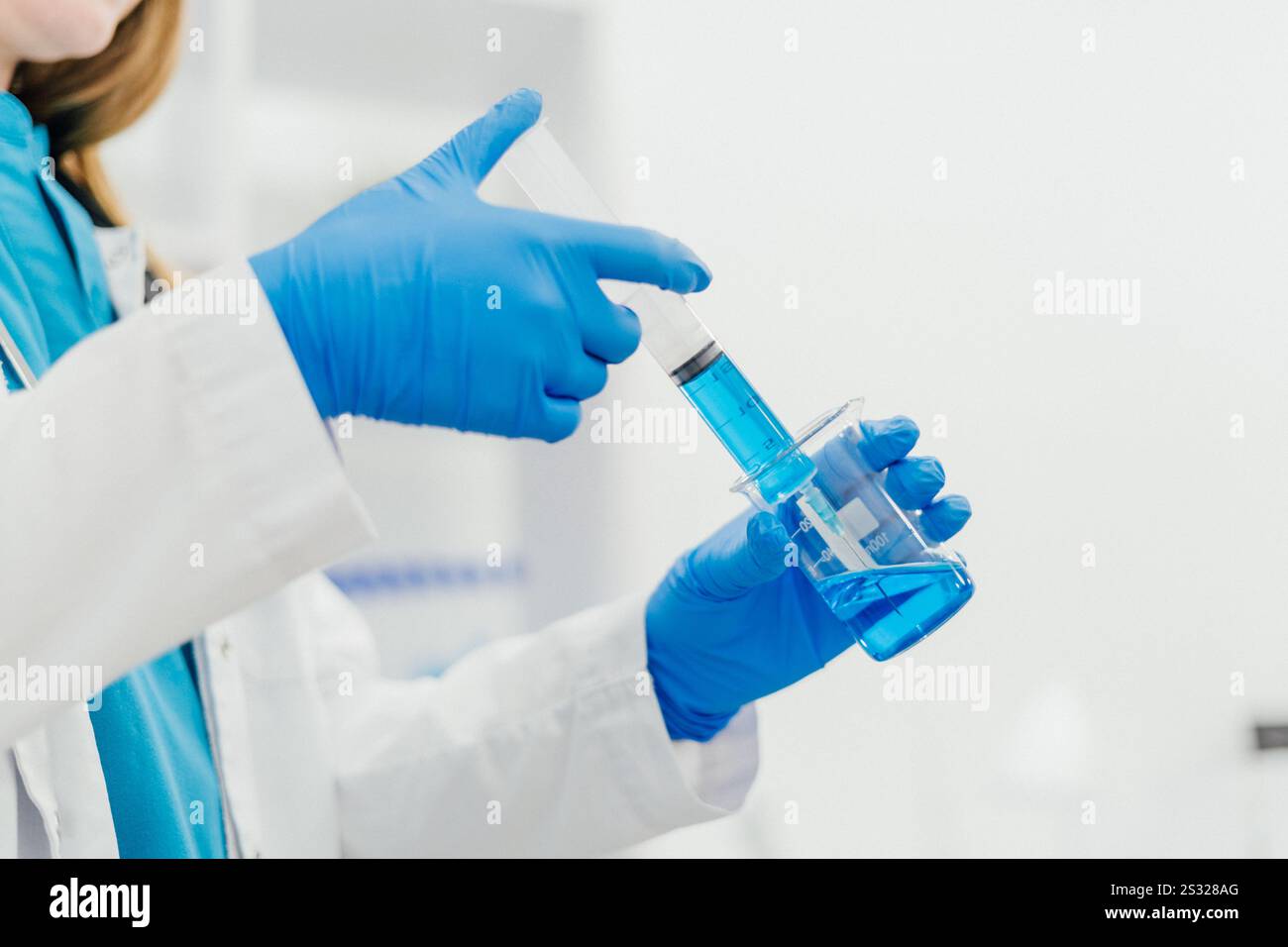 Close-up of hands wearing blue gloves handling a syringe and a ...