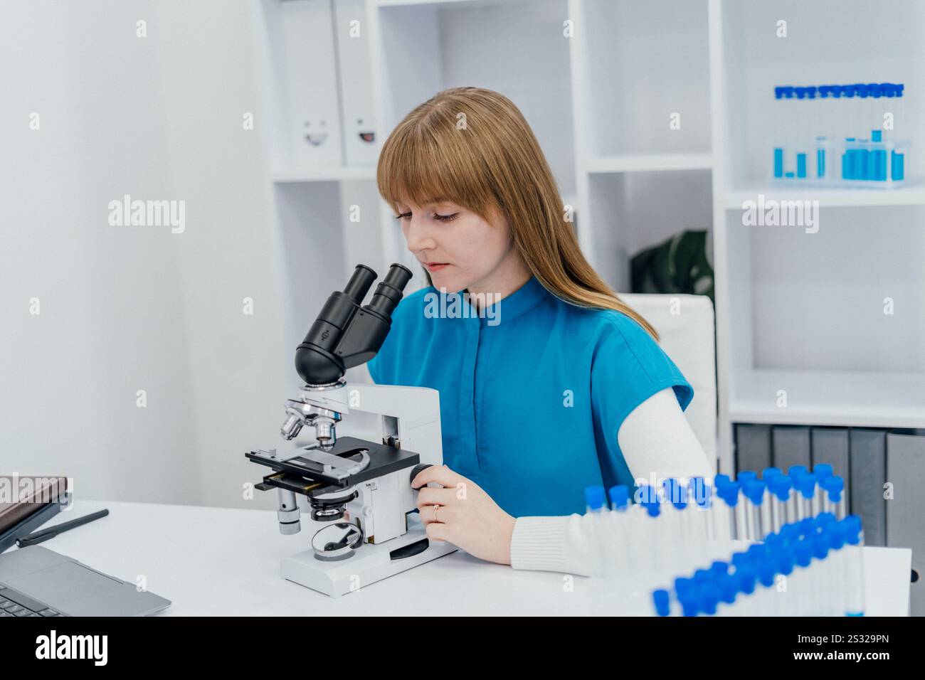 A young scientist wearing a blue uniform is focused on observing ...