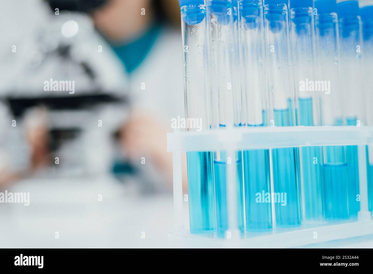 A close-up shot of a rack filled with test tubes containing blue liquid ...
