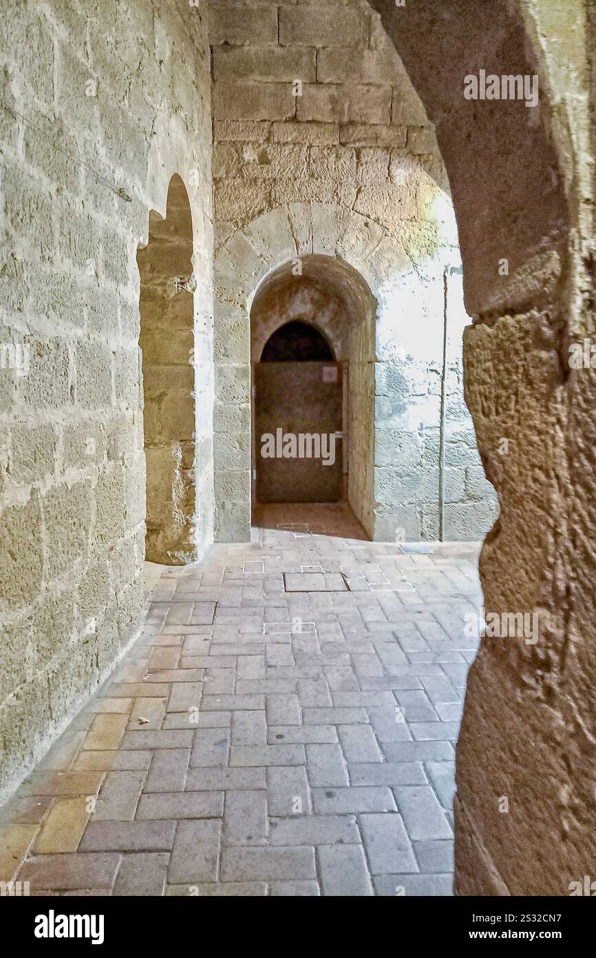 Rustic stone hallway with arched doorways, textured walls, and a sense ...