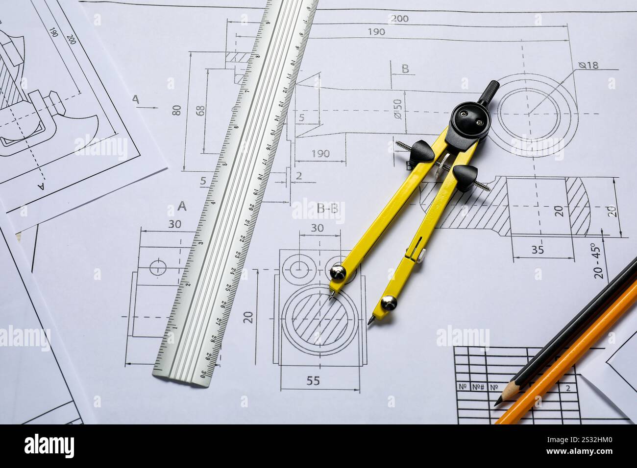 Different engineering drawings, pencils, ruler and divider on table ...