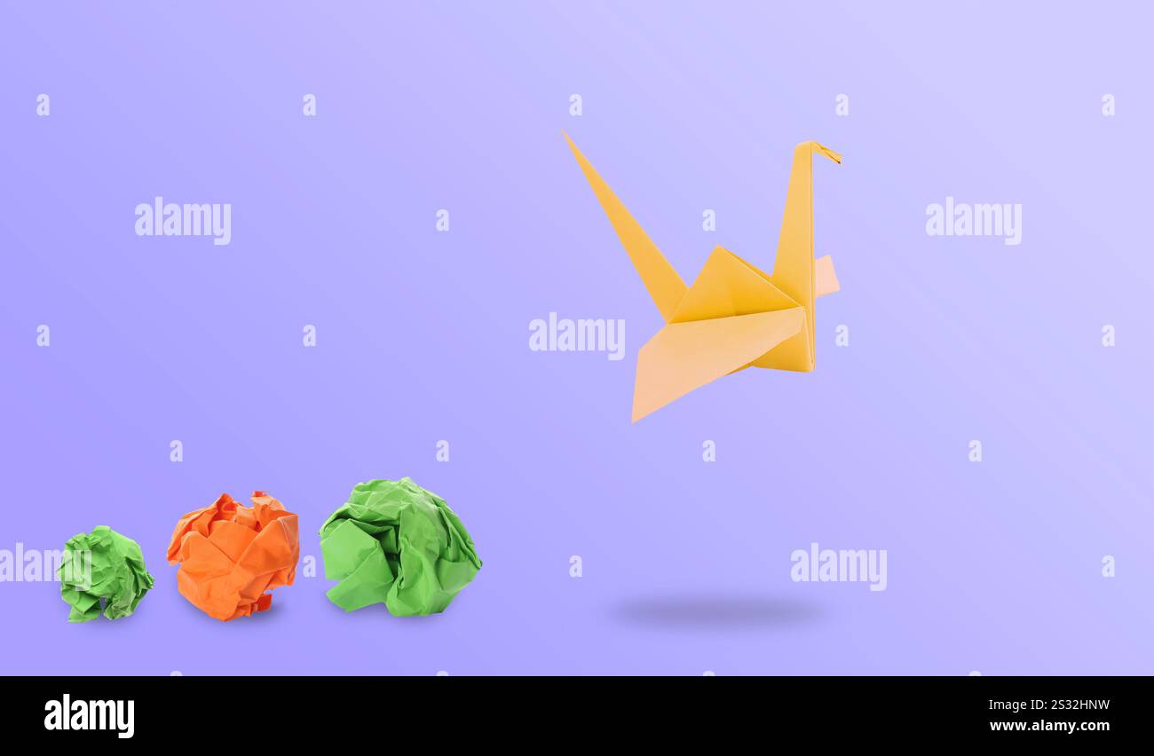 Orange origami crane and crumpled paper balls on violet gradient ...