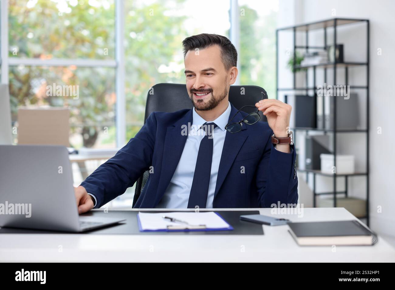 Happy banker working with laptop at table in office Stock Photo - Alamy