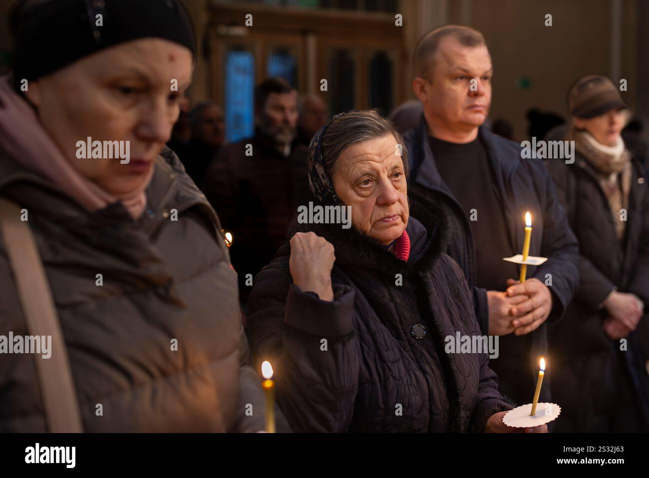 Believers hold candles and pray during the funeral ceremony of former ...