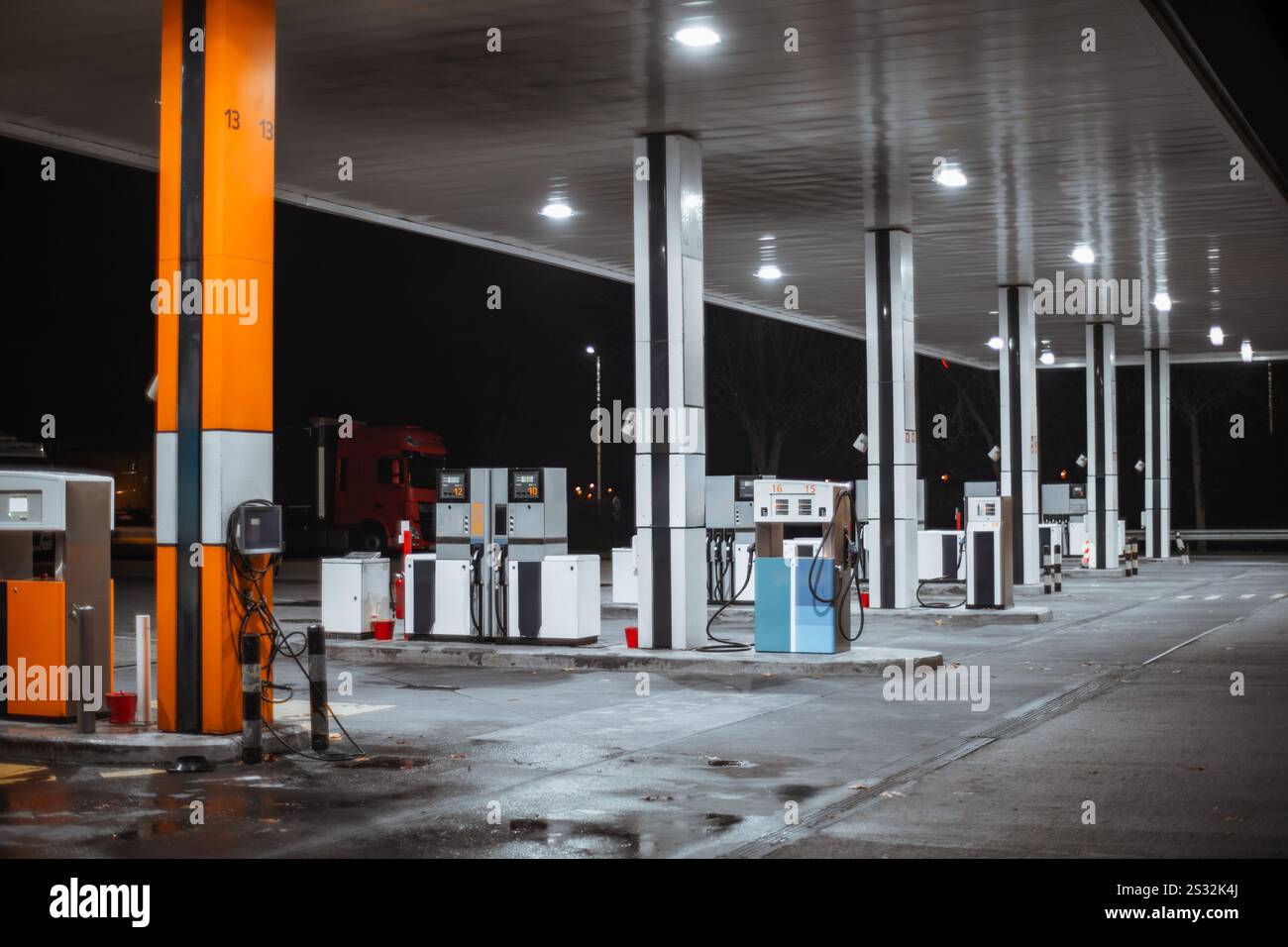 A modern gas station at night with illuminated fuel pumps under a ...