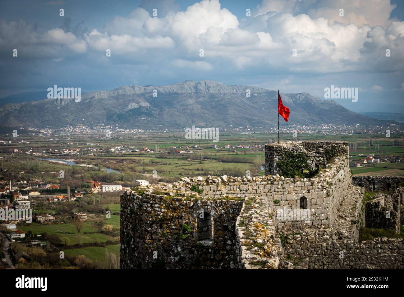 A vibrant red flag is waving proudly atop the remnants of an ancient ...