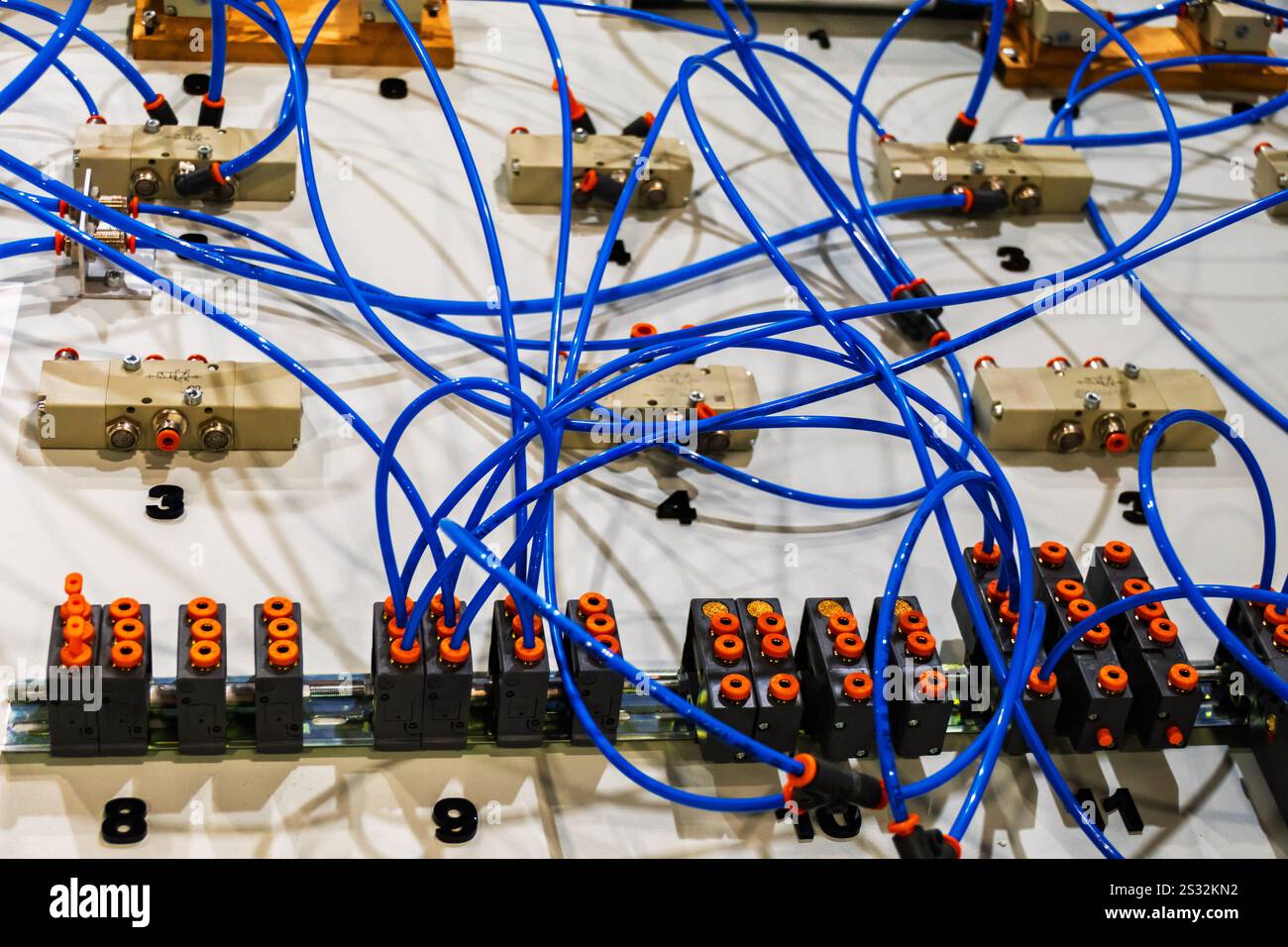 A close-up of a hydraulic training rig with numerous blue hoses and ...