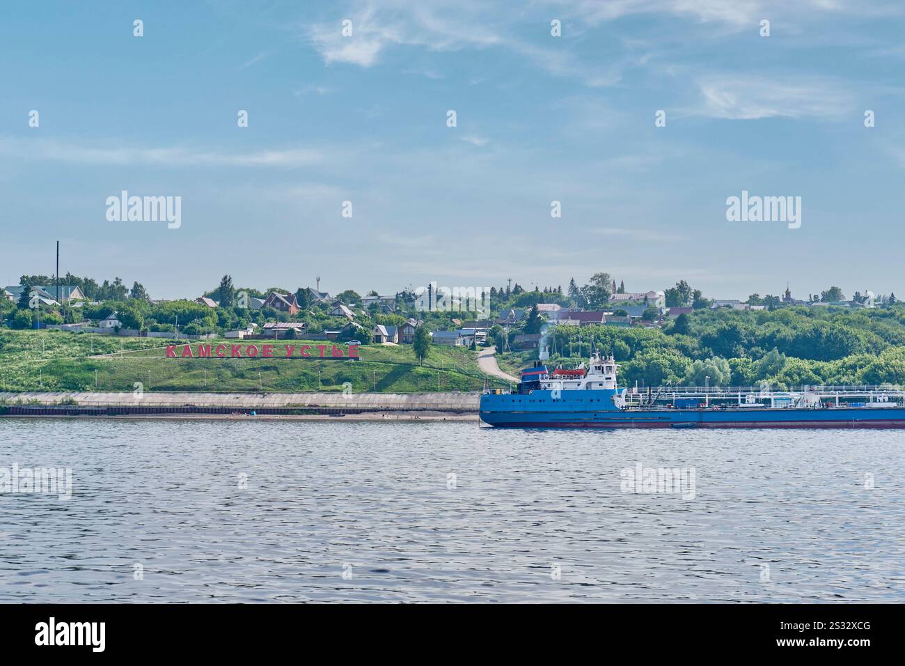 Scenic riverside view of Kamskoye Ustye village. Cargo ship cruising along river Volga, Russia ...