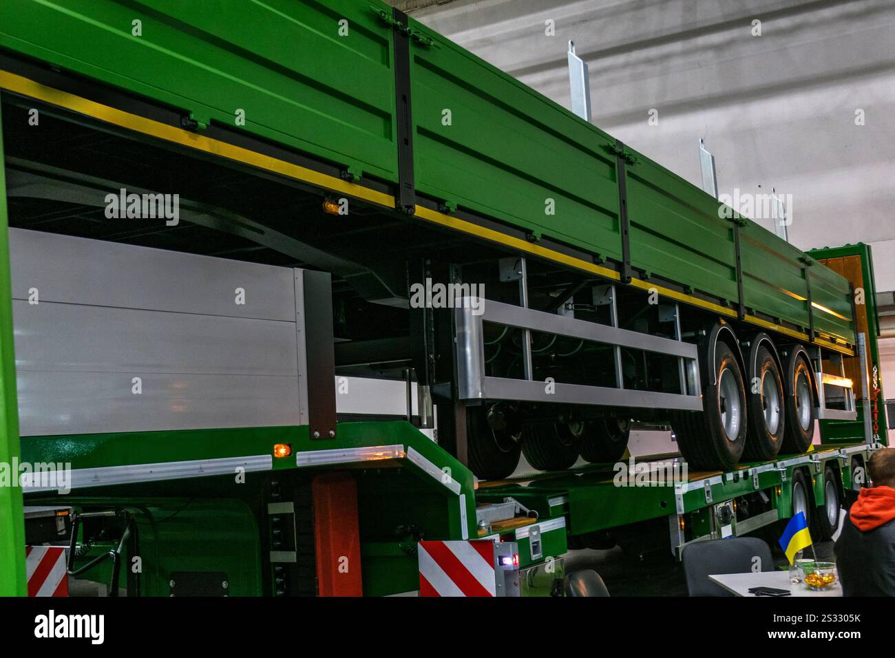 the rear of a large green truck. It is equipped with a low-bed platform ...