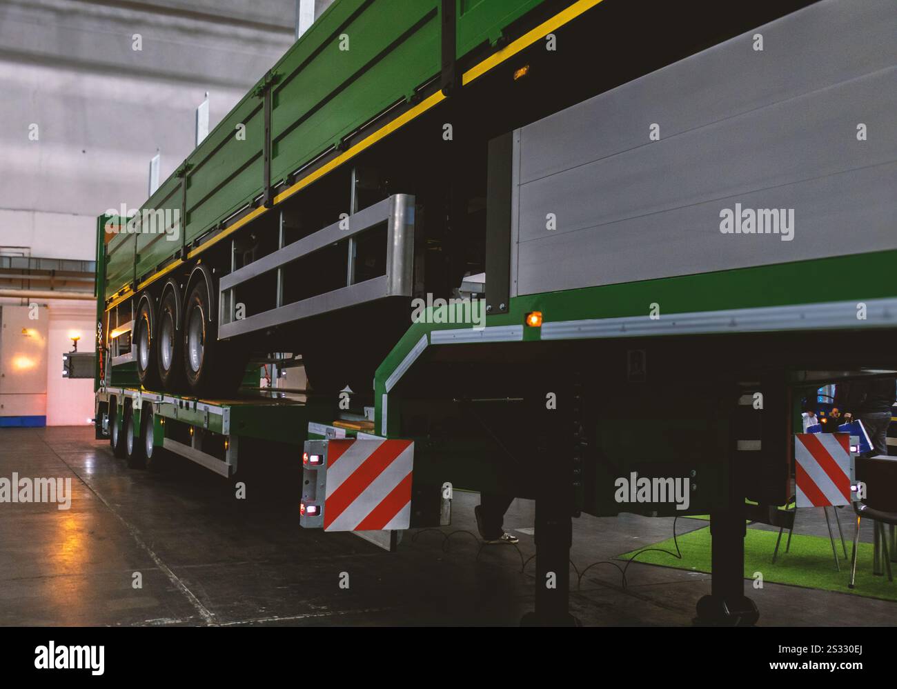 the rear of a large green truck. It is equipped with a low-bed platform ...