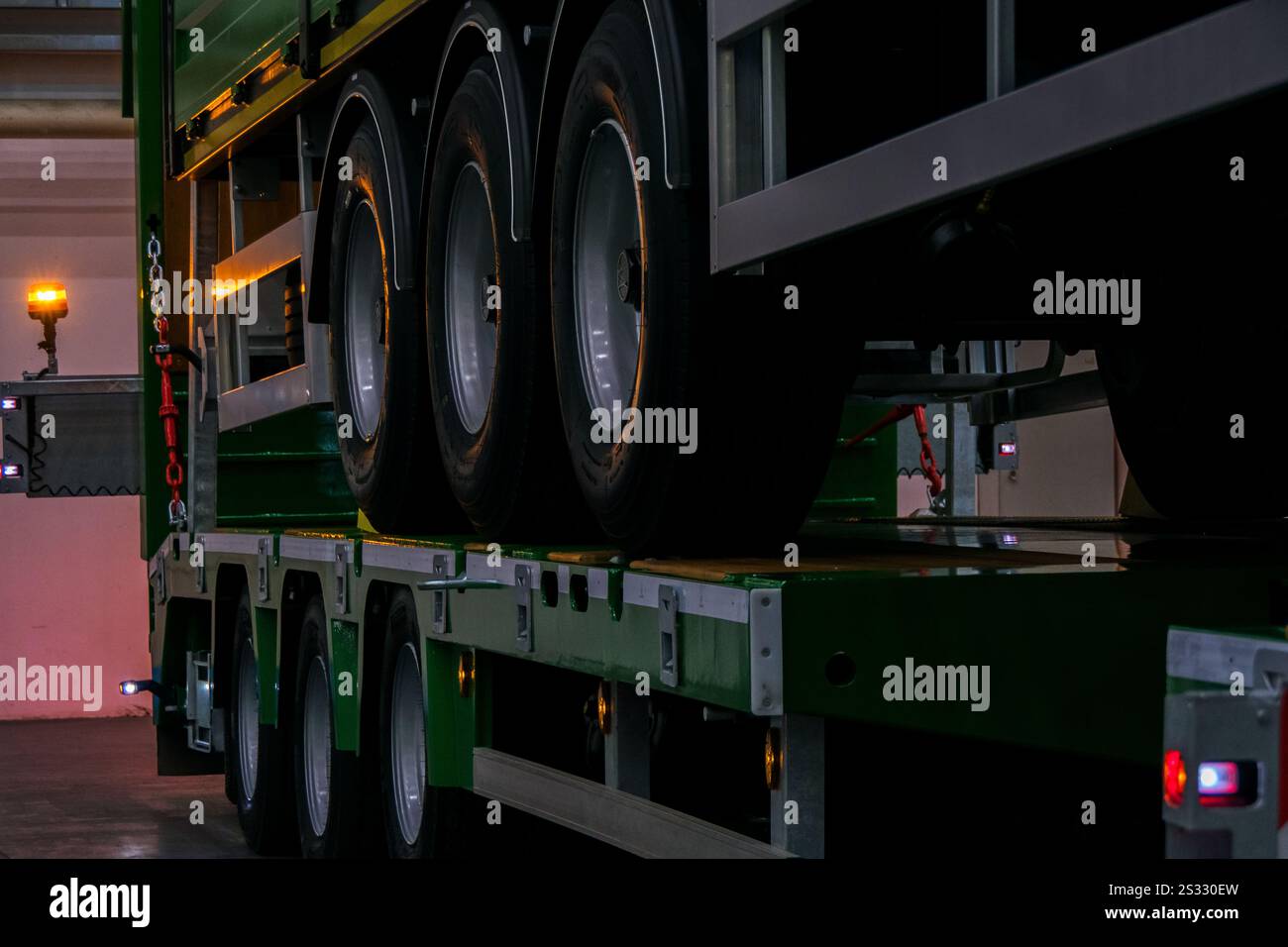 the rear of a large green truck. It is equipped with a low-bed platform ...