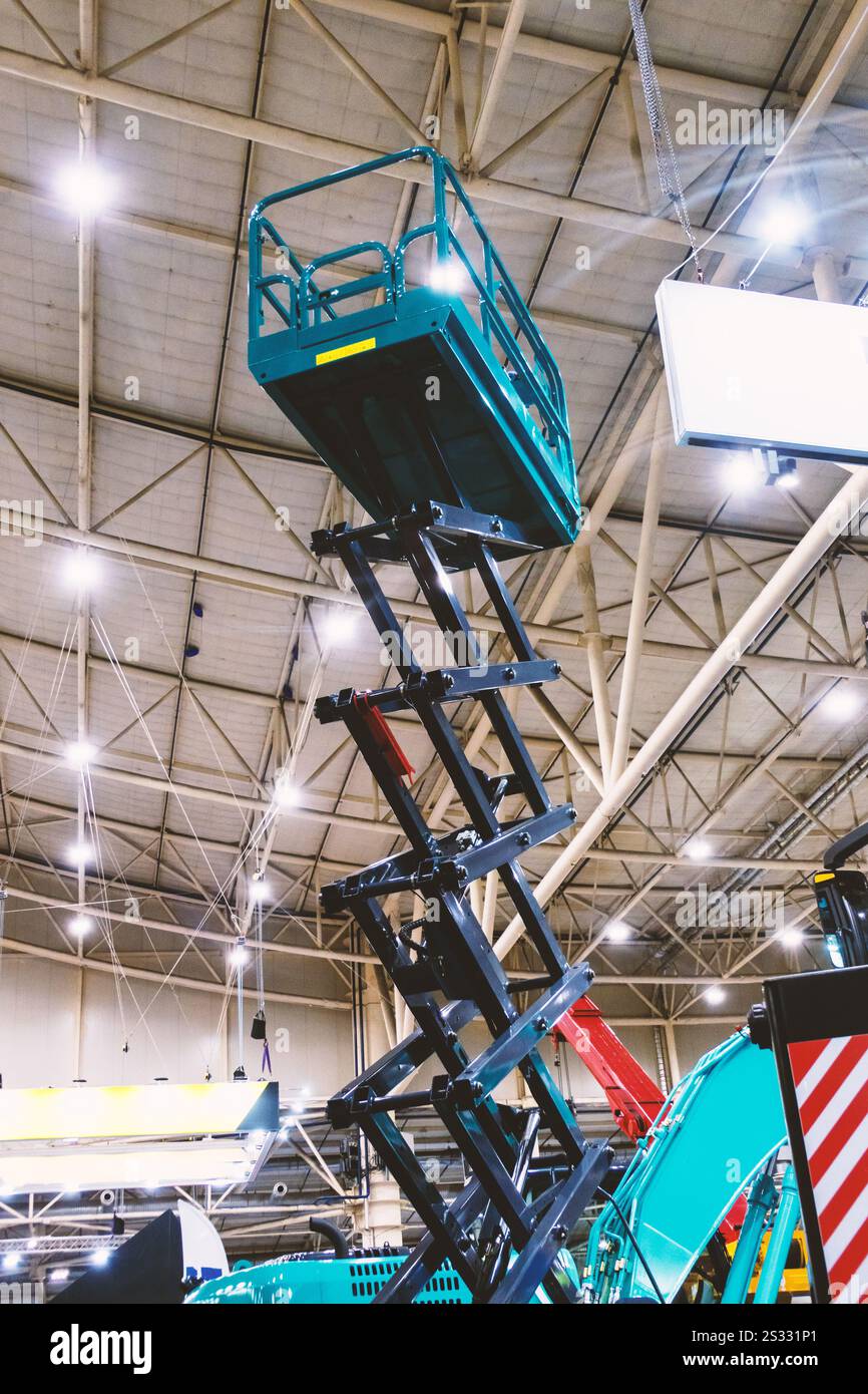 A blue scissor lift is positioned in a large industrial or warehouse ...