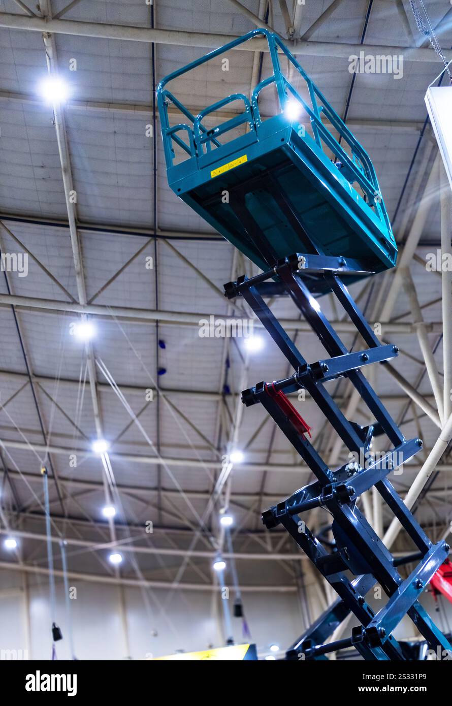A blue scissor lift is positioned in a large industrial or warehouse ...