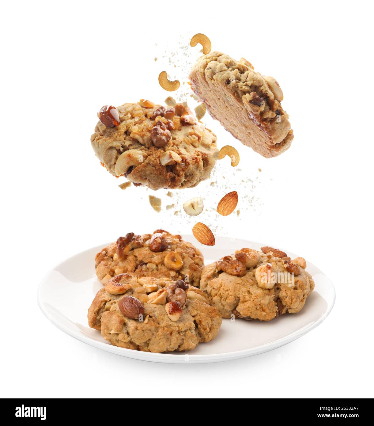Yummy nut cookies falling onto plate on white background Stock Photo ...