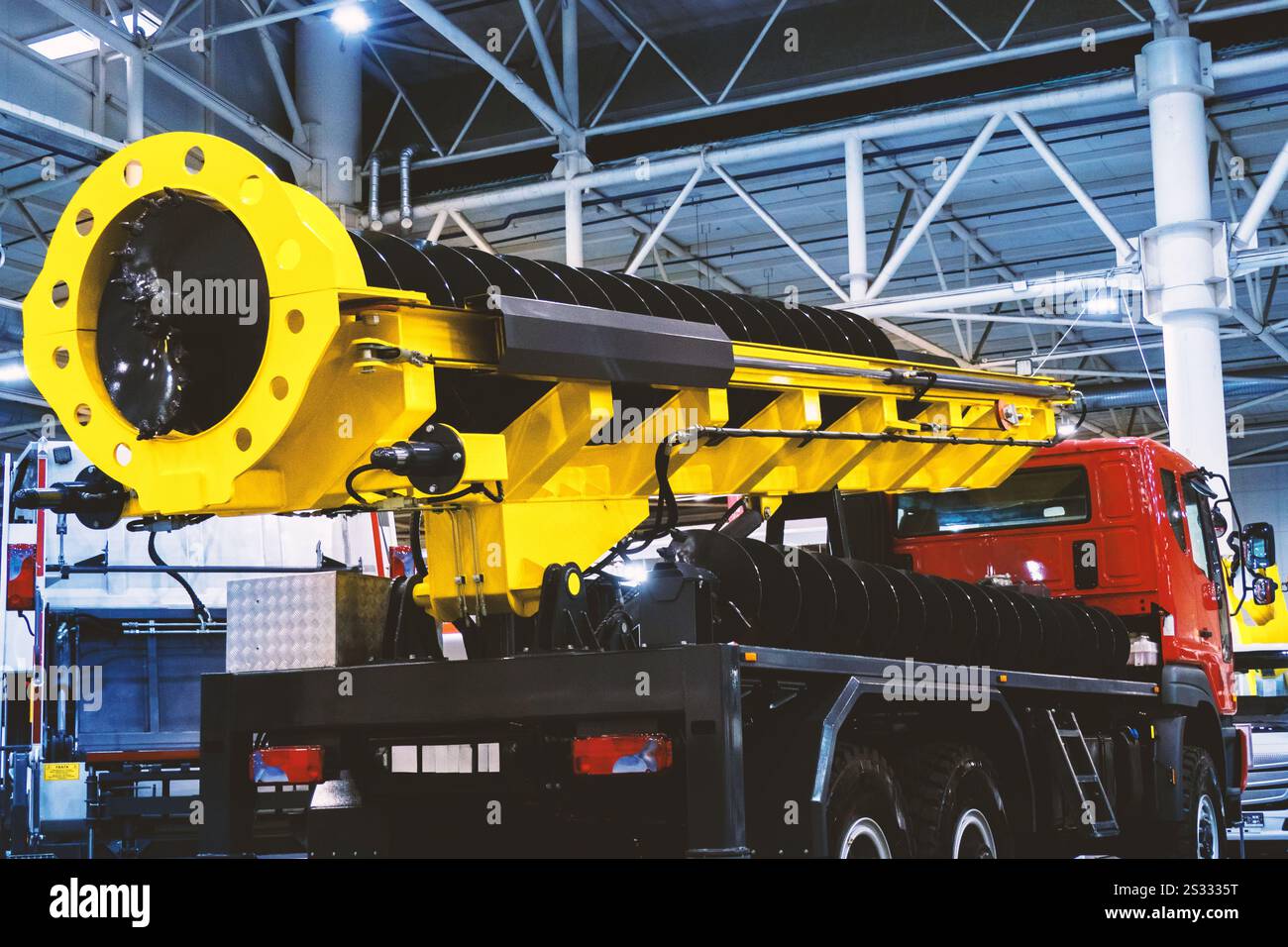 A drilling rig mounted on a truck, featuring a yellow boom and drilling ...
