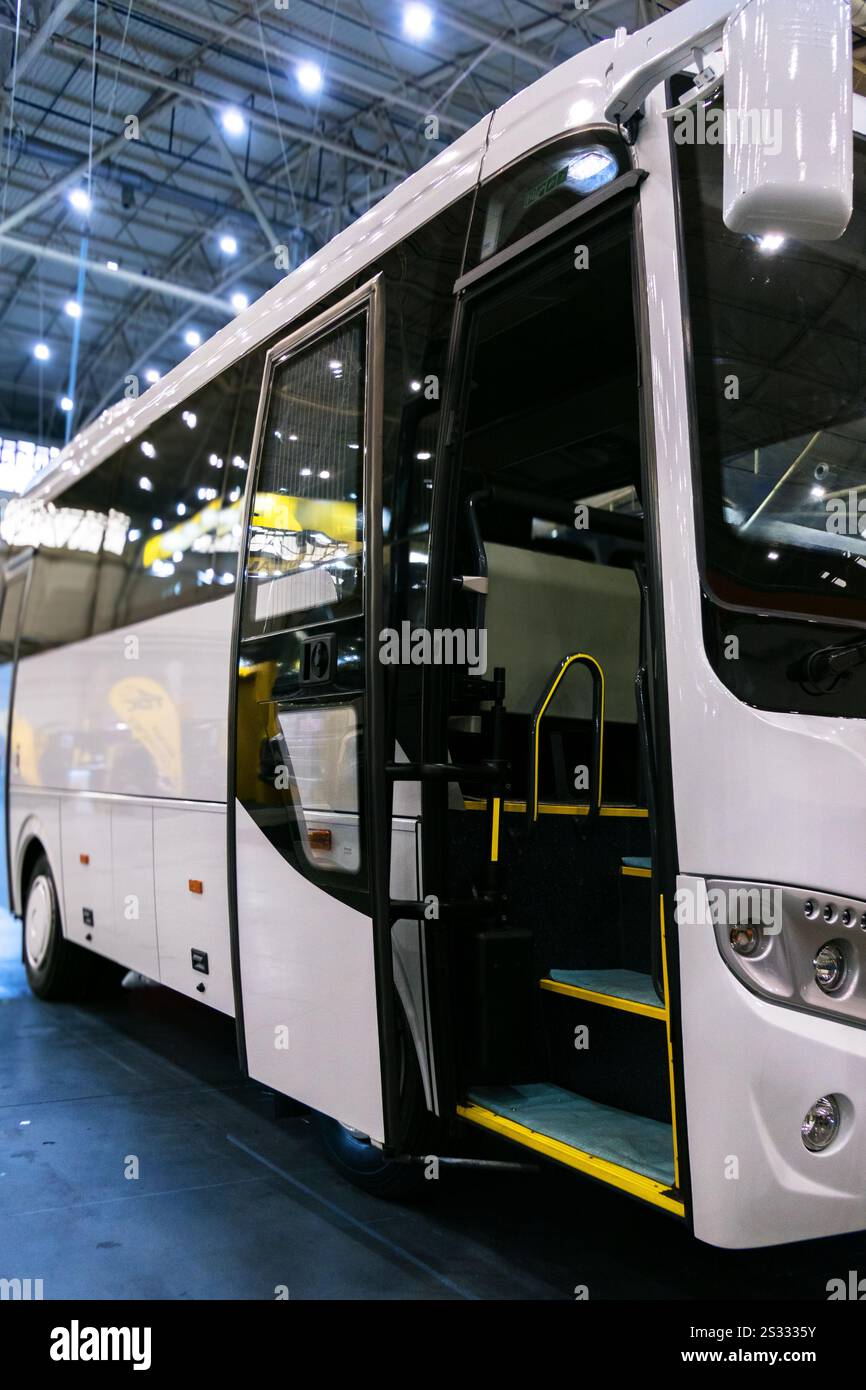 A white tourist bus with open doors is depicted. Steps with yellow ...