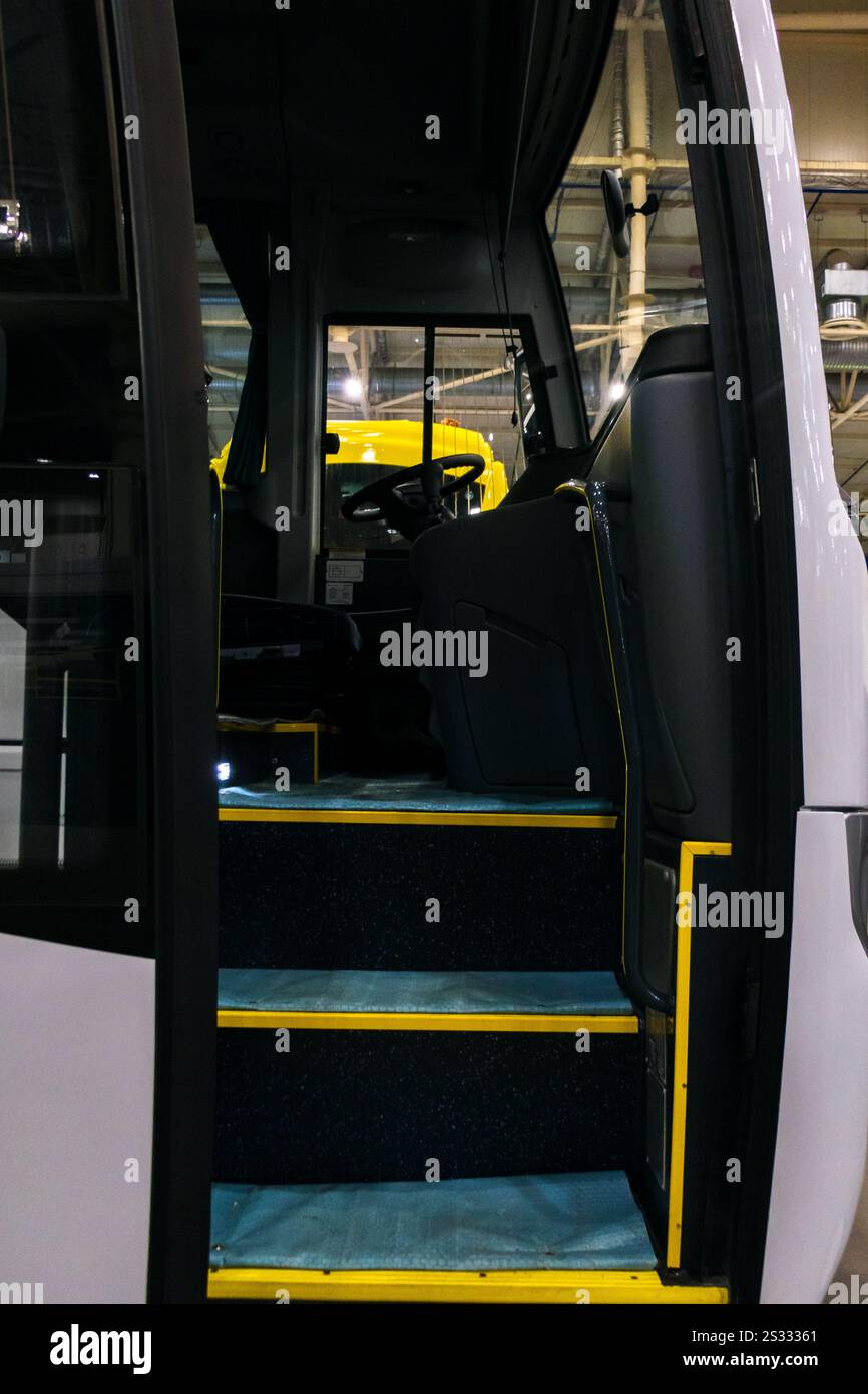 A white tourist bus with open doors is depicted. Steps with yellow ...